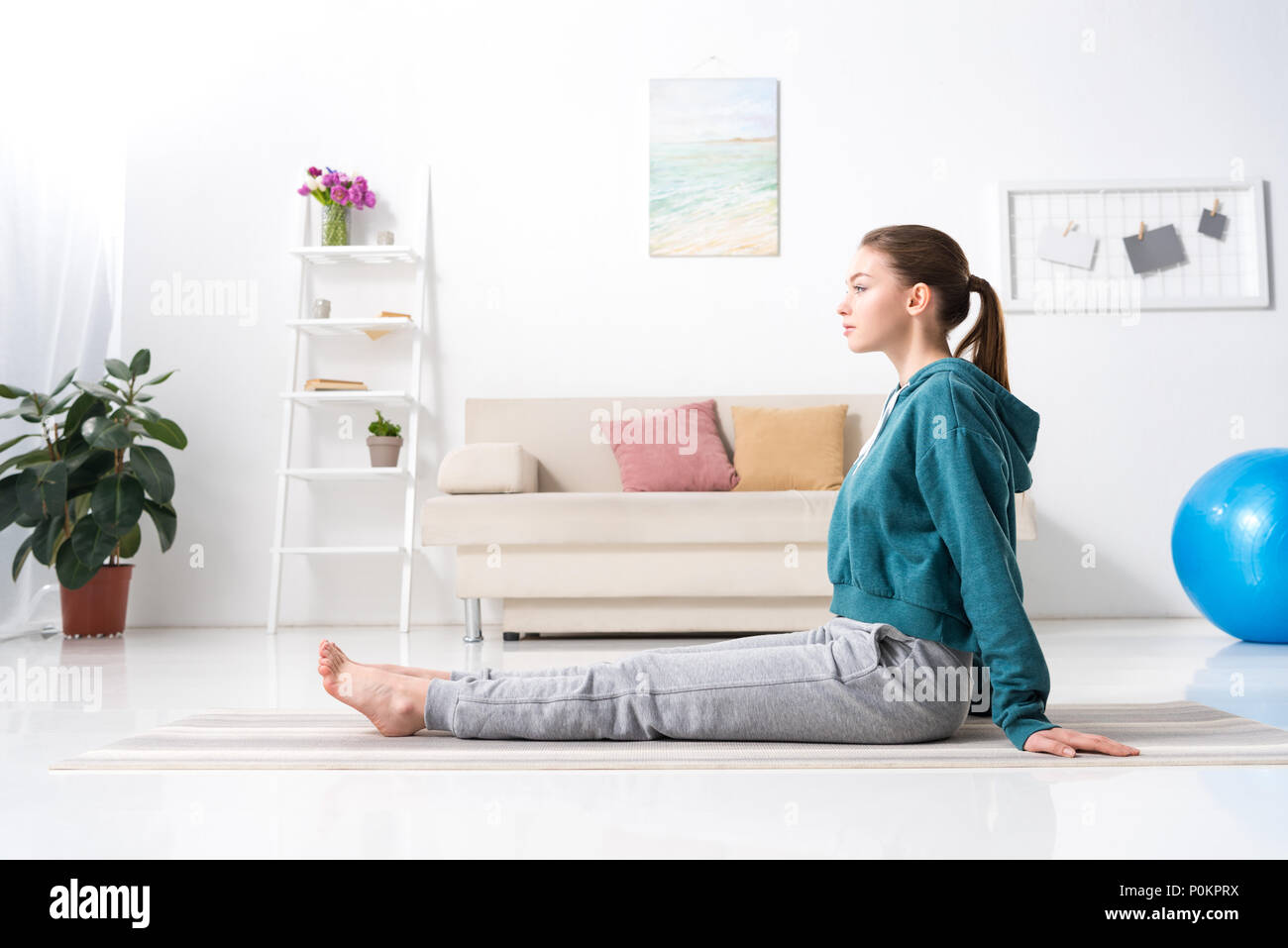 side view of girl sitting on yoga mat at home Stock Photo - Alamy
