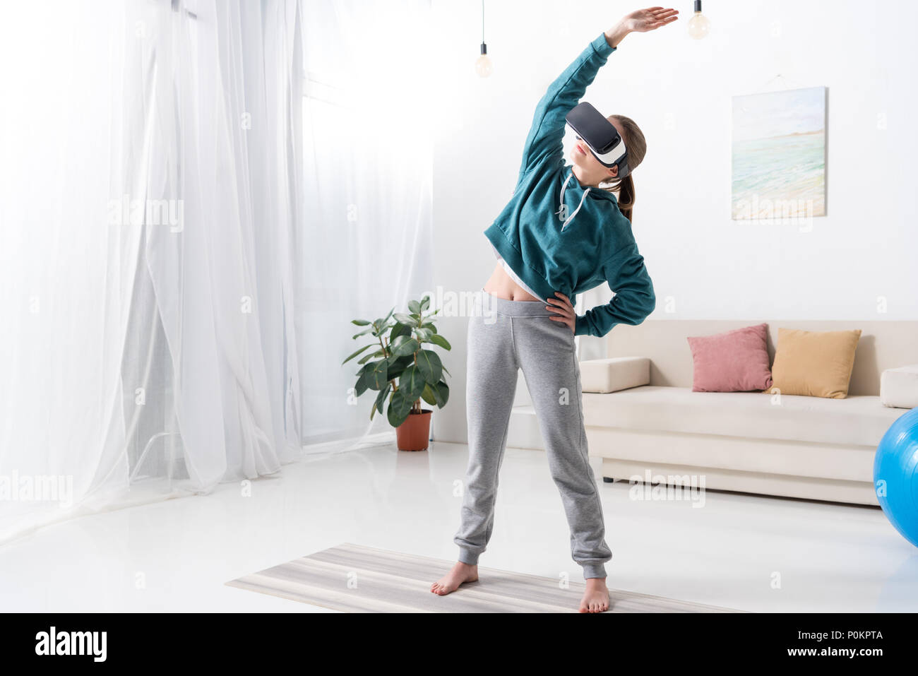 girl standing and stretching with virtual reality headset on yoga mat ...