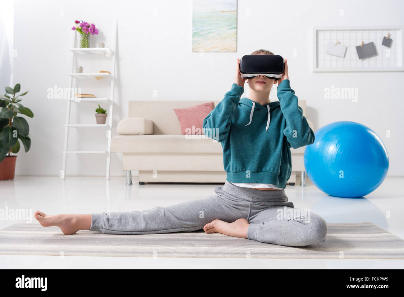 sportive girl stretching with virtual reality headset on yoga mat at ...