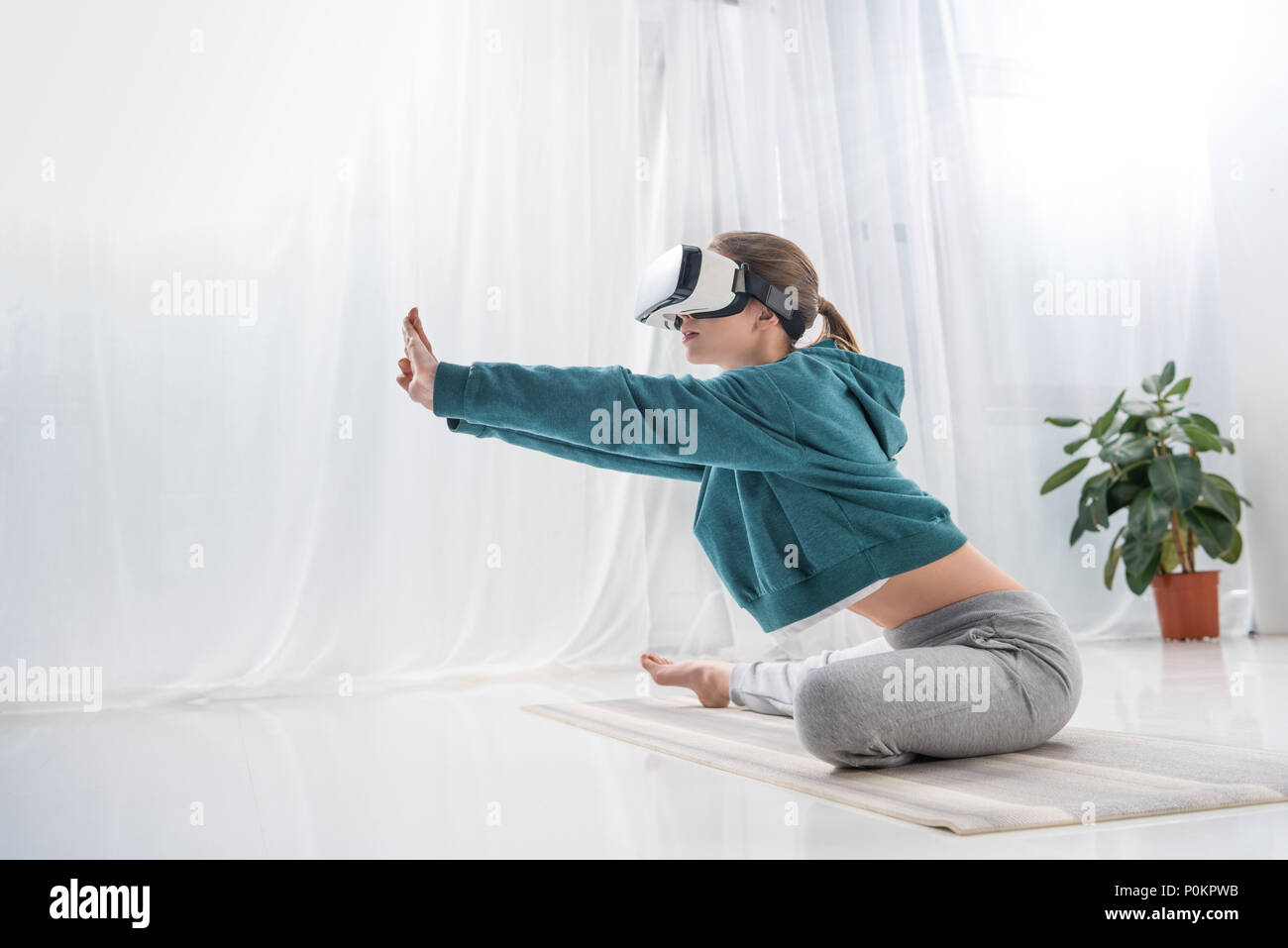 side view of girl stretching with virtual reality headset on yoga mat ...