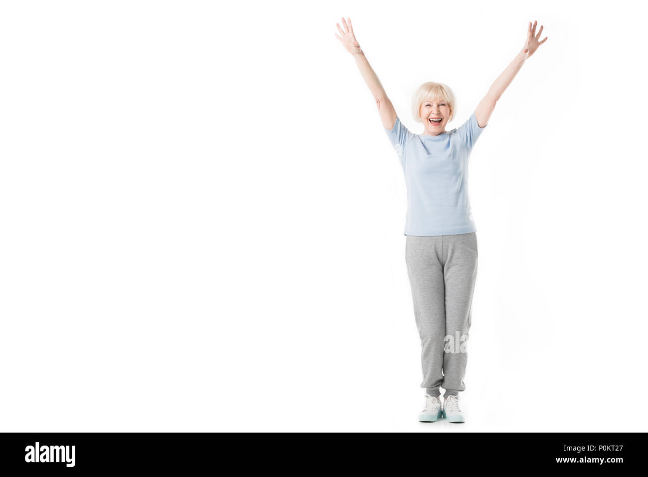 Happy senior sportswoman standing with arms up isolated on white Stock ...