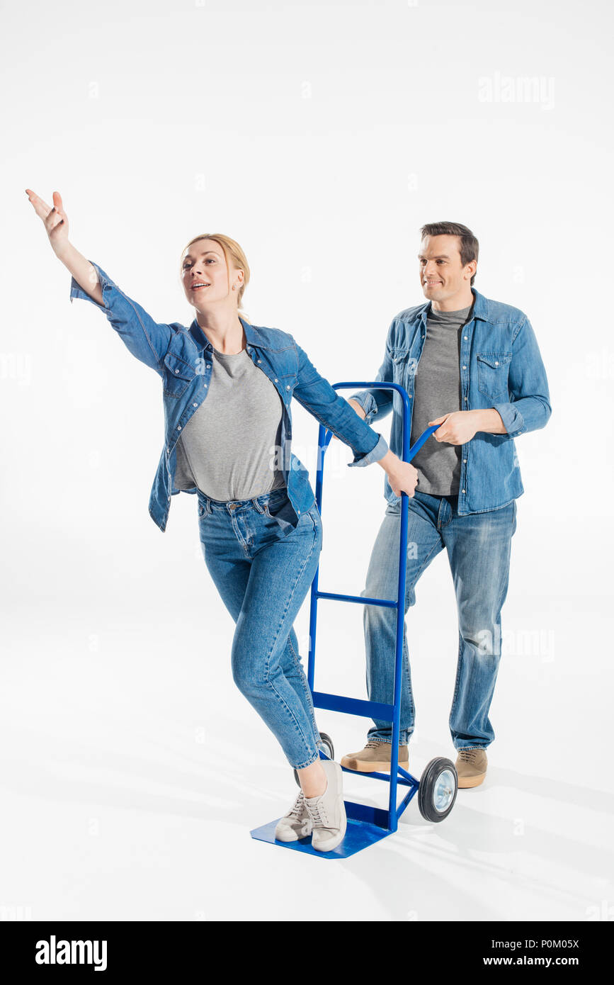 Man holding trolley cart with woman fooling around isolated on white ...
