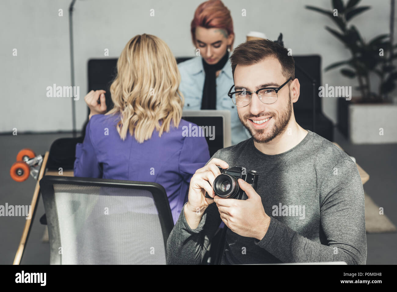 selective focus of smiling photographer looking at camera with ...