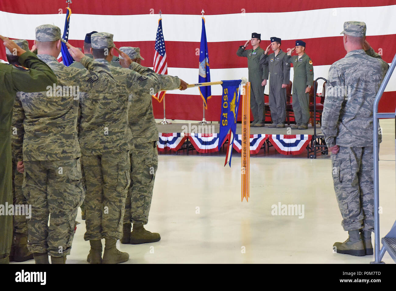 Airmen from the 550th Fighter Squadron salute during the playing of the National Anthem during a ...