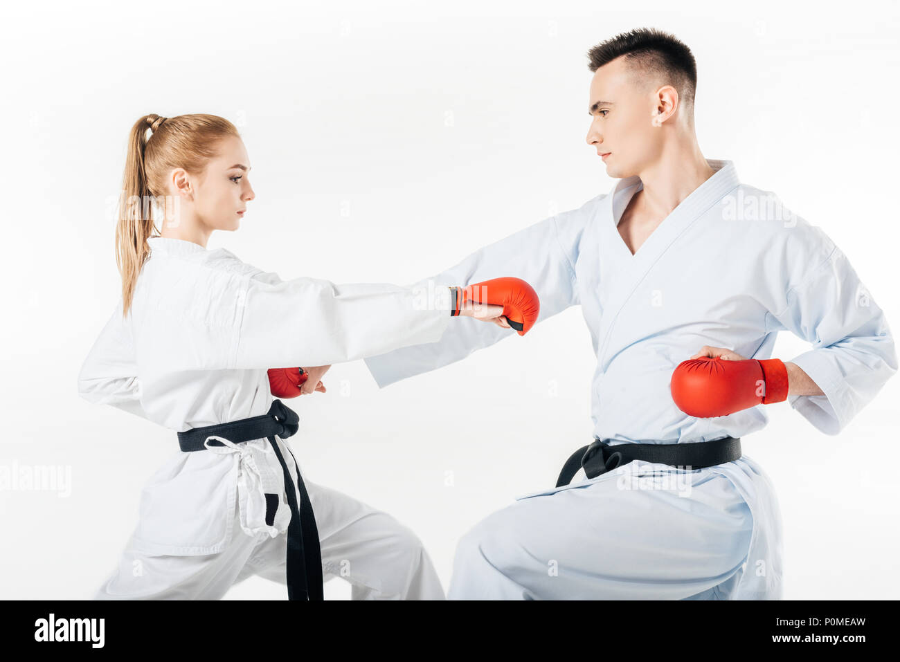 side view of karate fighters training in kimono and red gloves isolated ...