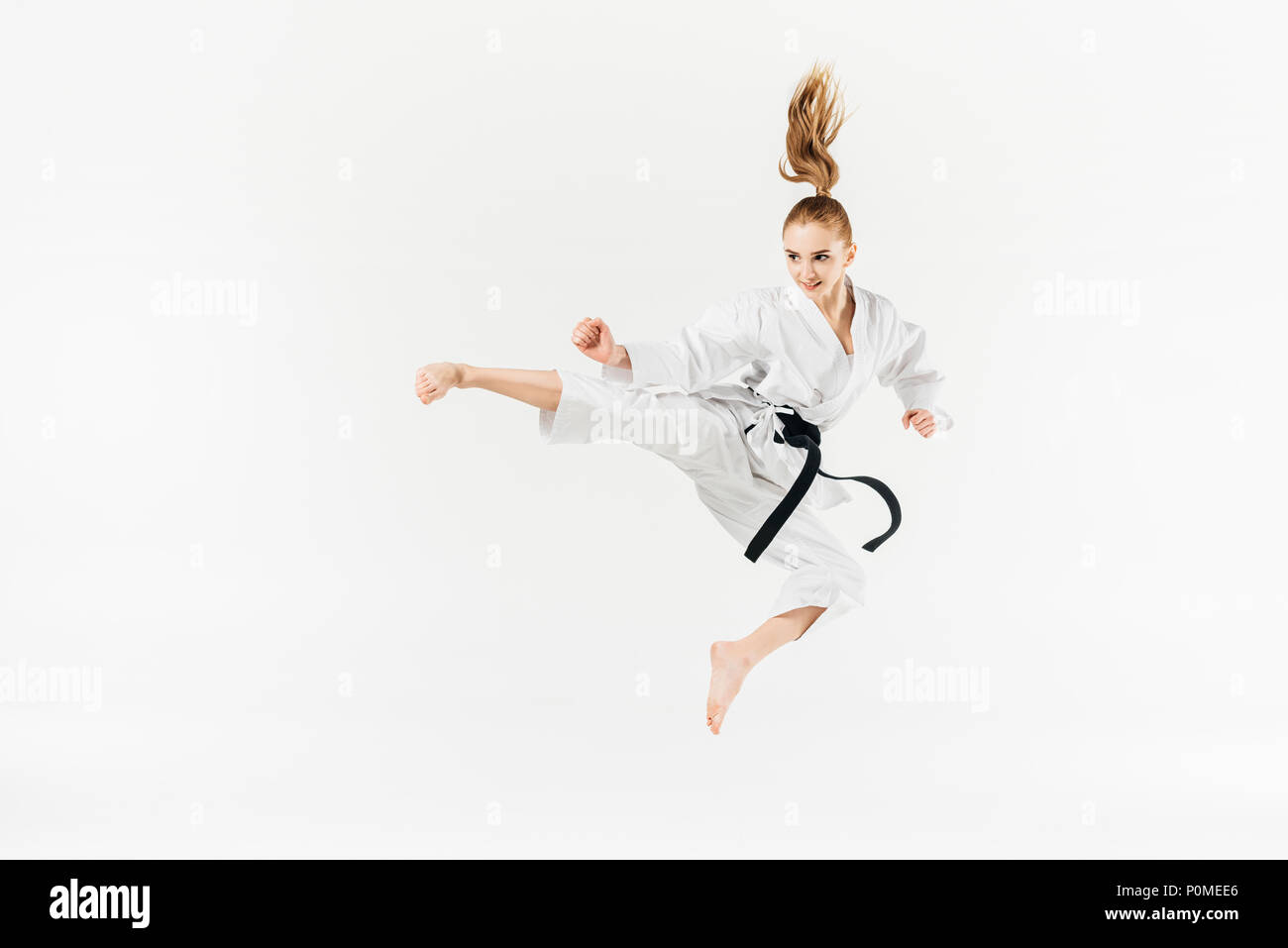 female karate fighter jumping and performing kick isolated on white ...