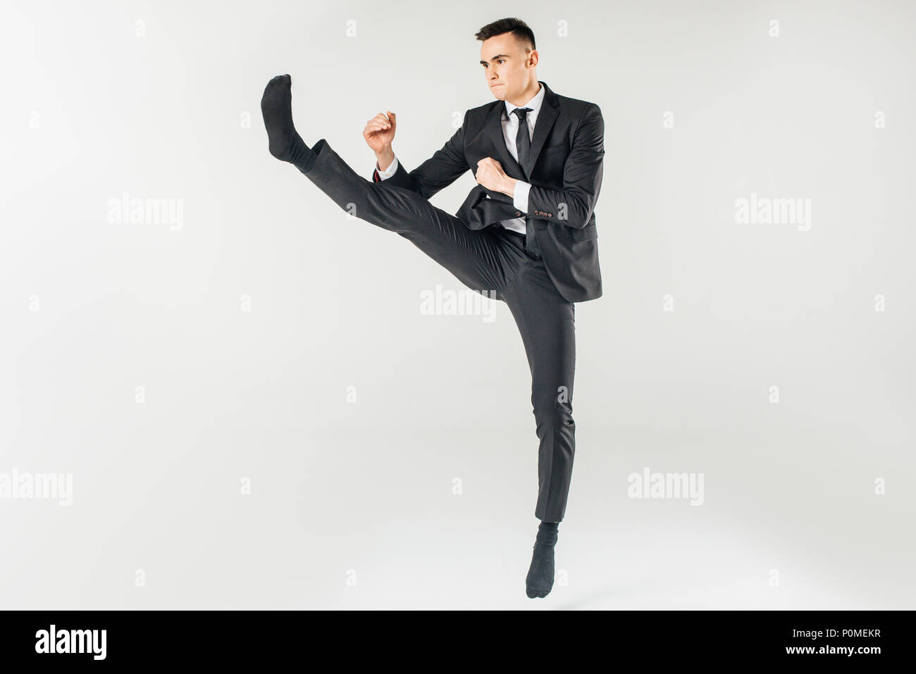 businessman jumping and performing kick in suit isolated on white Stock ...