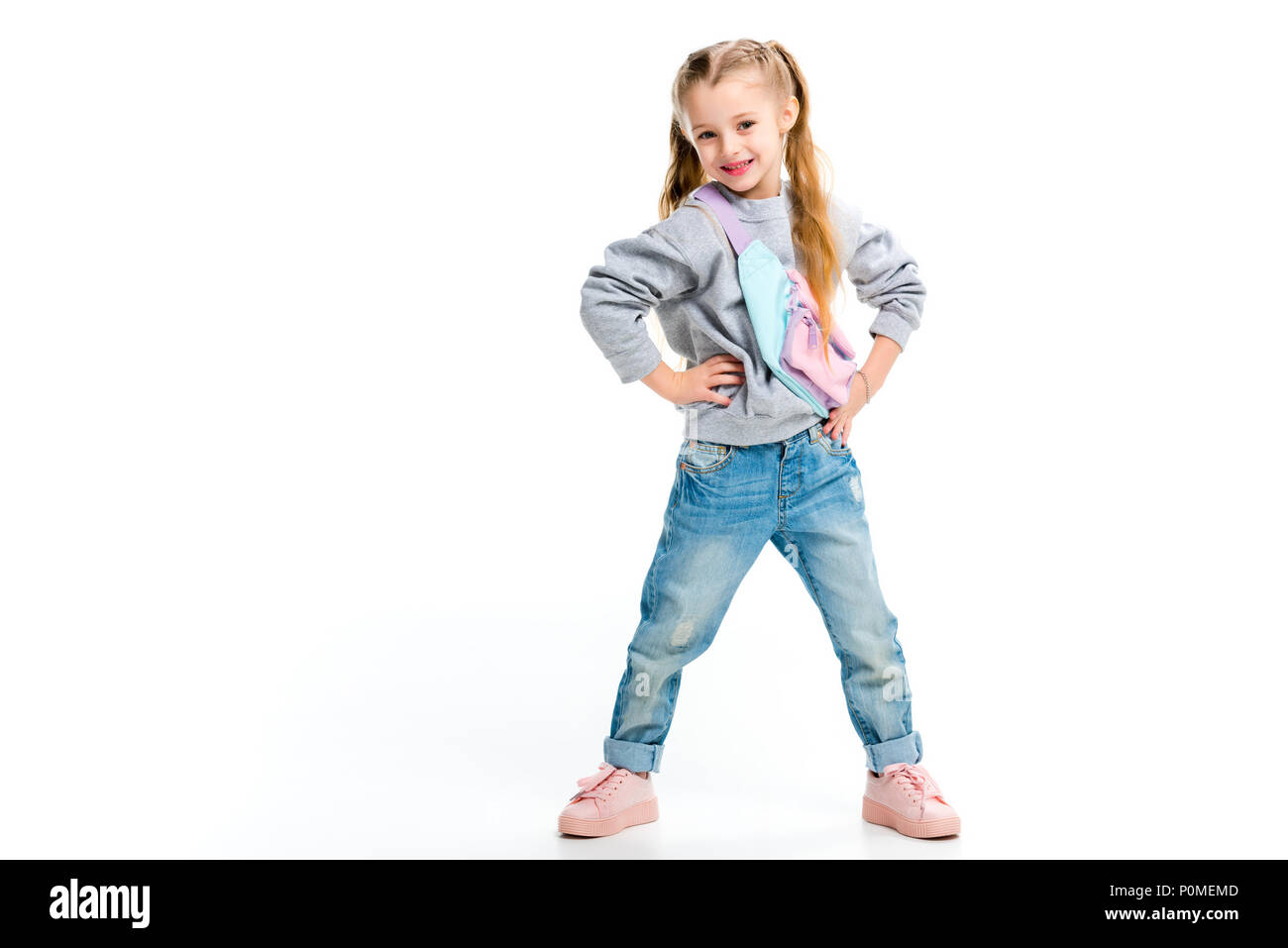 Stylish child standing with arms on thighs isolated on white Stock ...