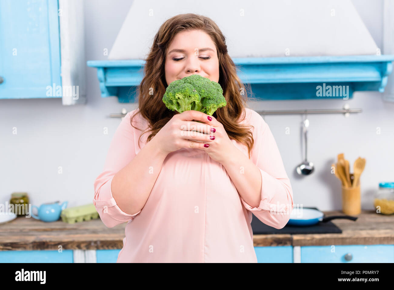 Overweight young woman eating broccoli hi-res stock photography and ...