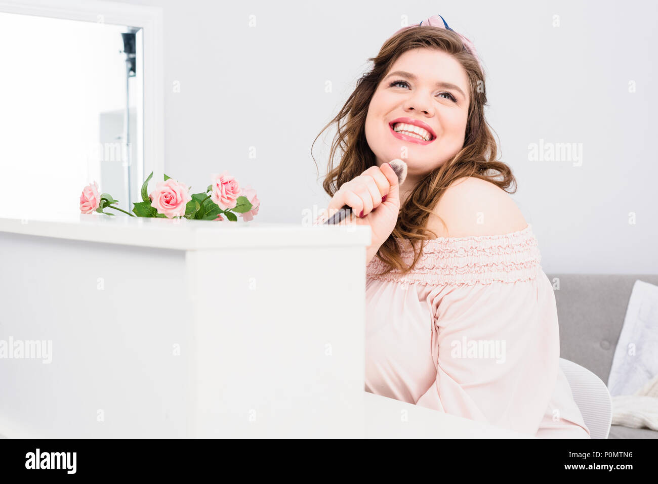 emotional young woman singing with makeup brush in hand as microphone ...