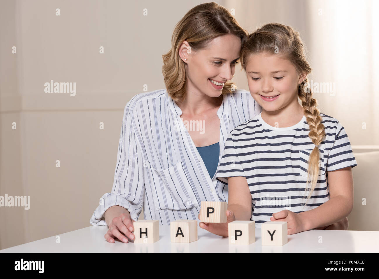 Girl and her mother composing word Happy using wooden cubes Stock Photo ...