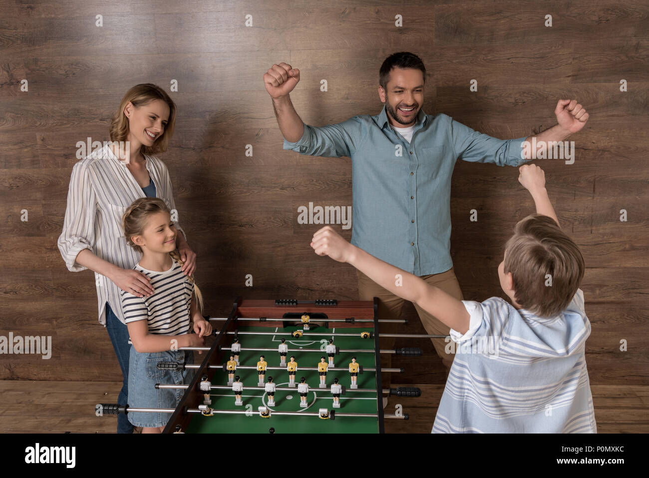 Happy smiling family playing foosball together Stock Photo - Alamy