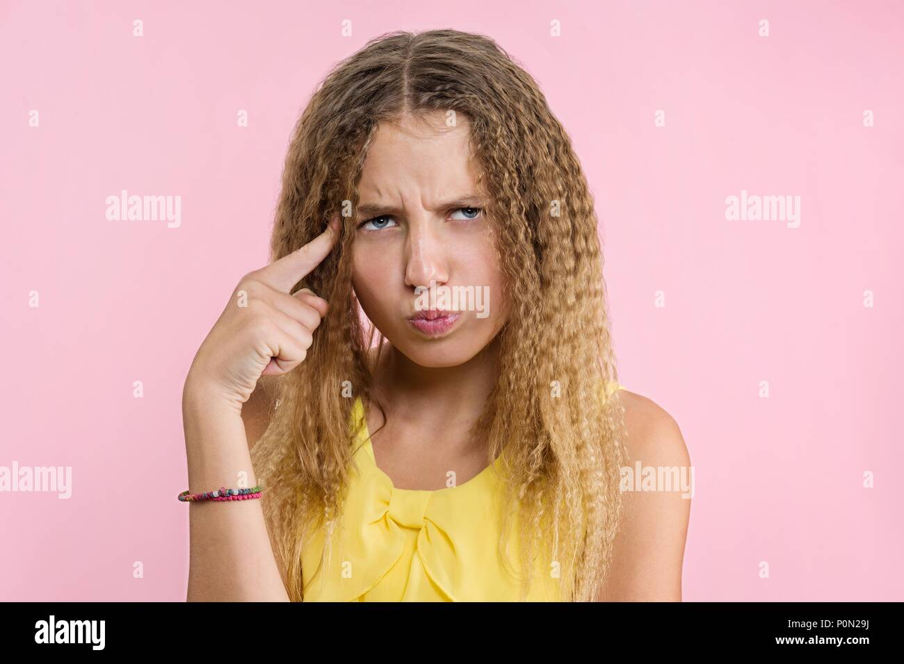 Teenage girl blonde with curly hair frowning, frowning her eyebrow ...