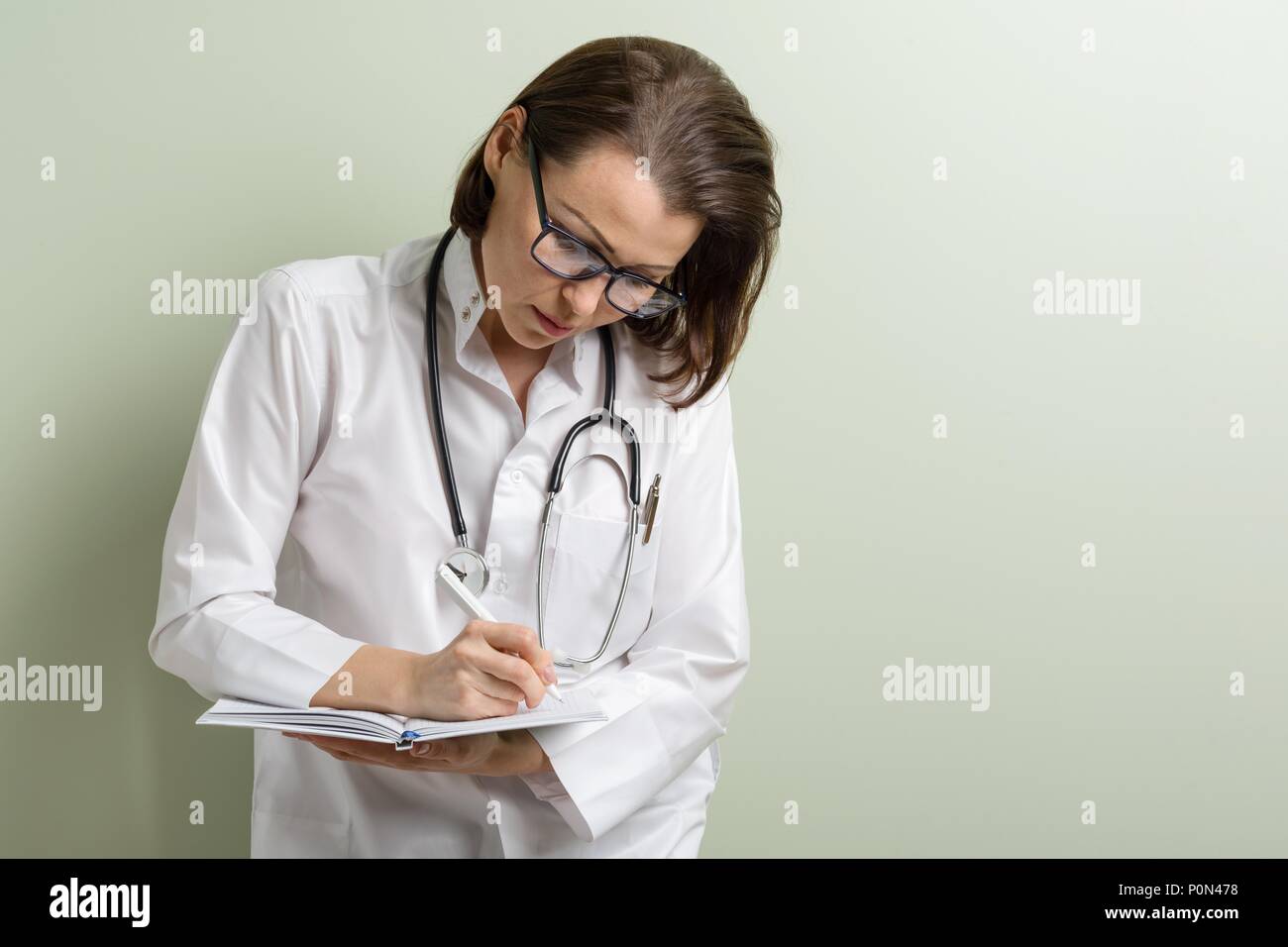 Medical doctor woman with stethoscope taking notes on her notepad ...
