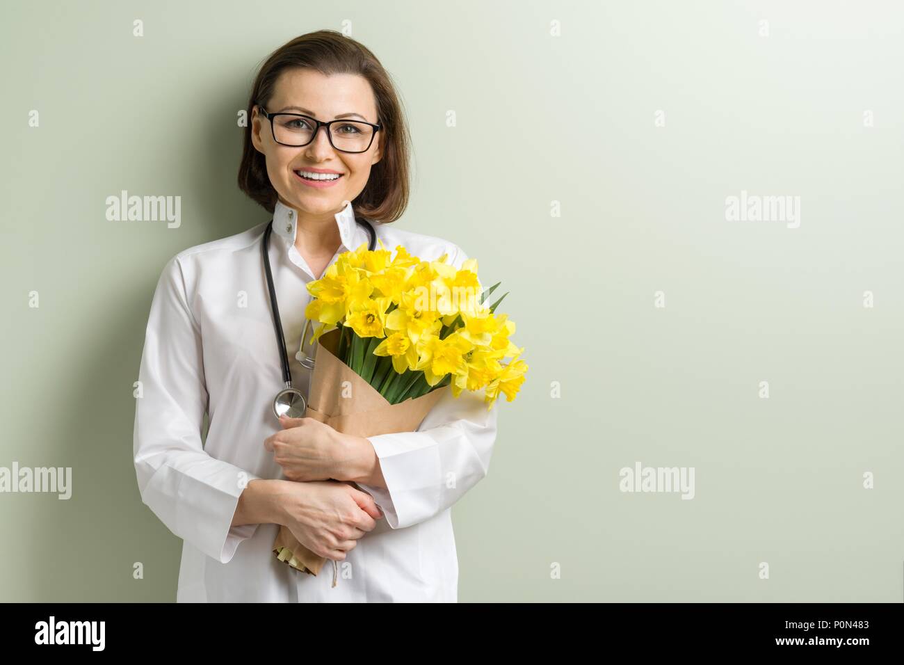 Smiling woman doctor with bouquet of flowers. World health day, doctors ...
