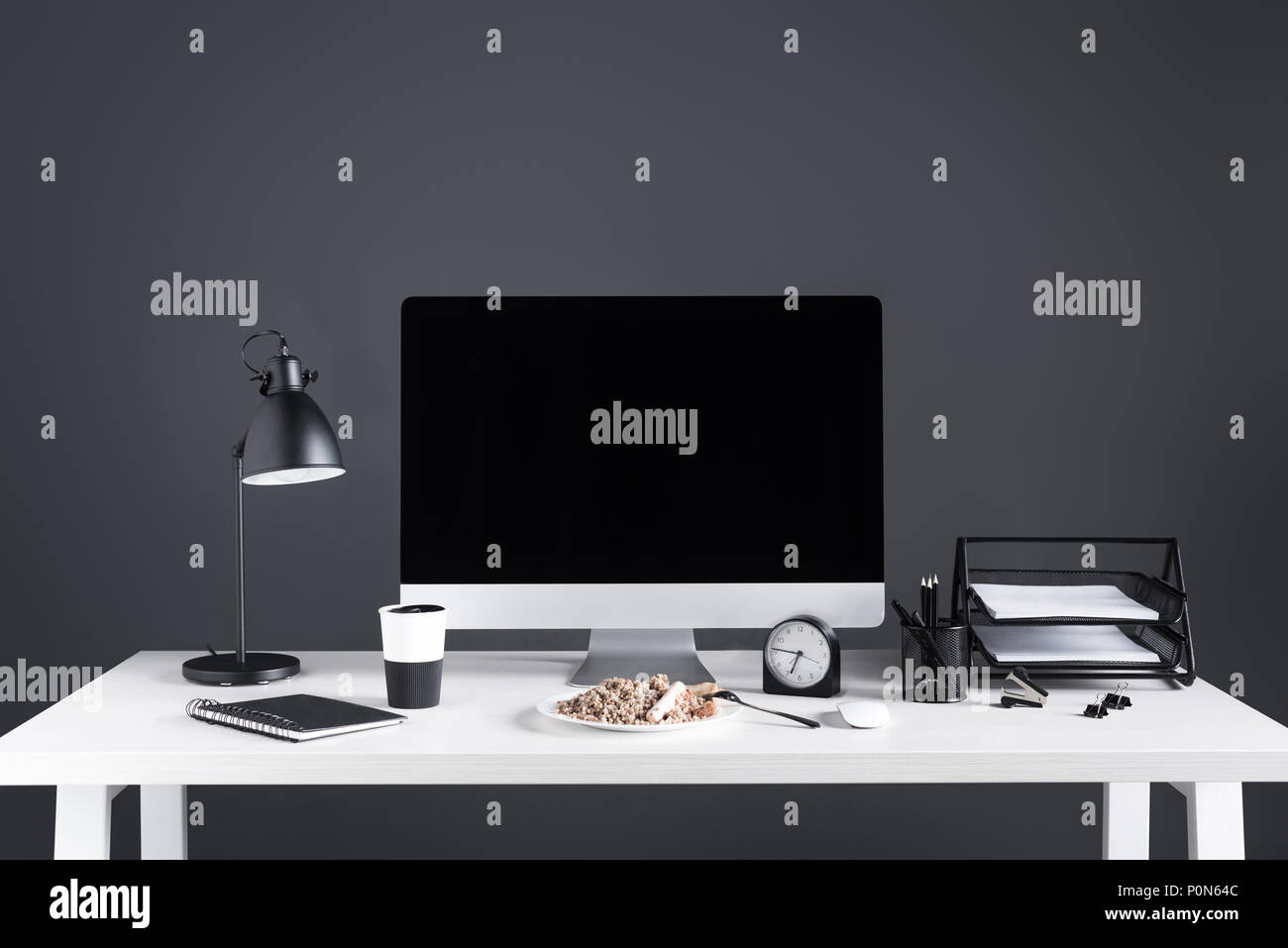desktop computer with blank screen, food on plate and office supplies ...