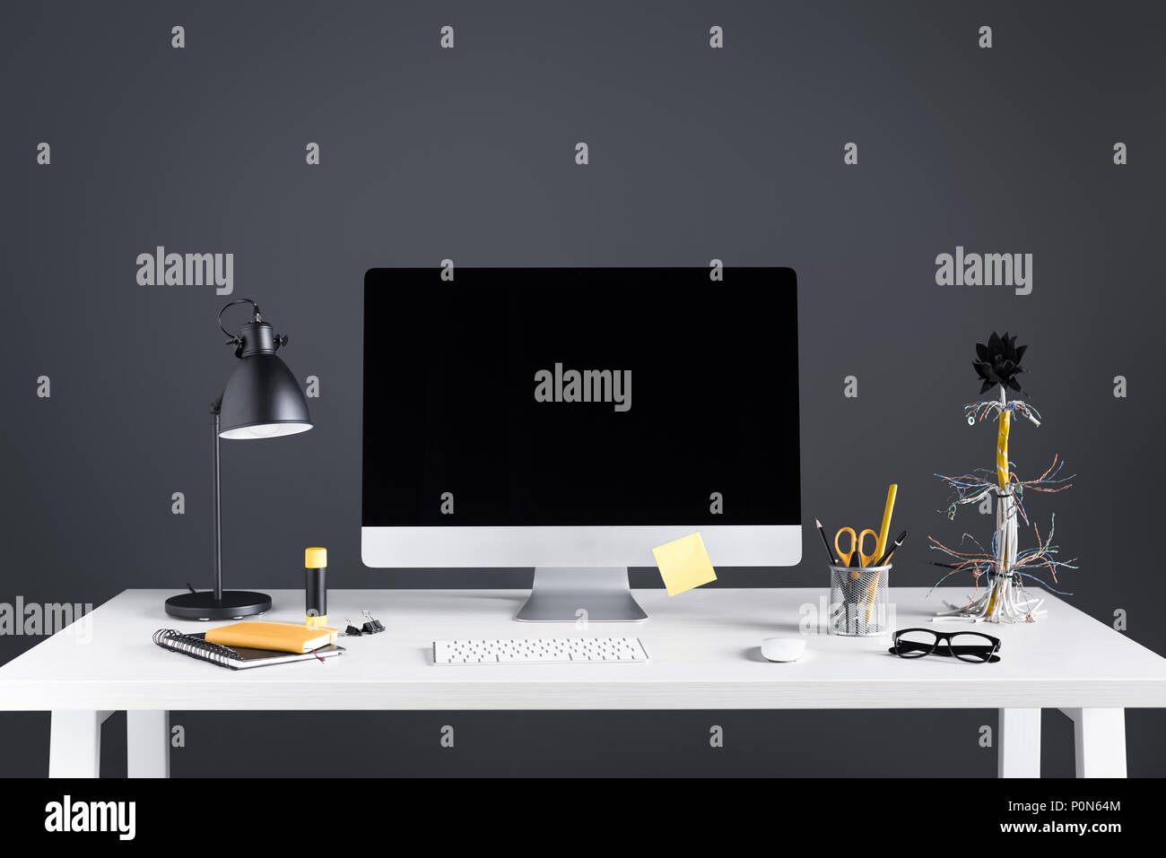 desktop computer with blank screen, lamp and office supplies on table ...