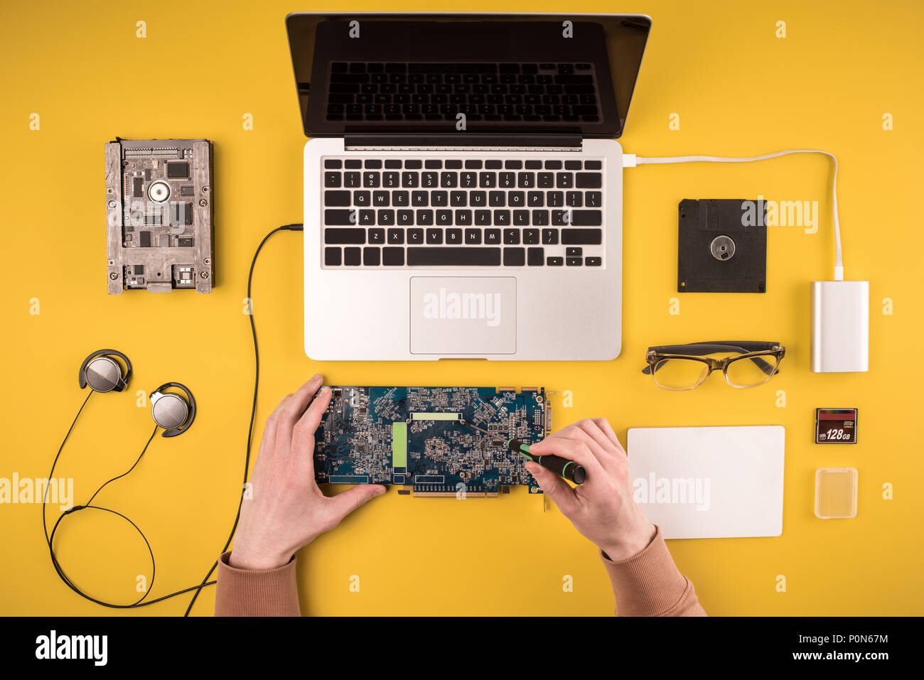 partial top view of person fixing laptop on yellow Stock Photo - Alamy