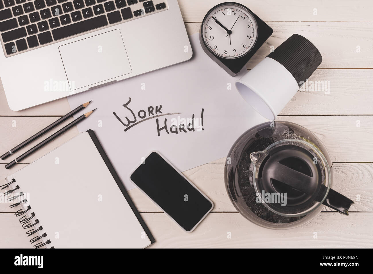 top view of laptop, coffee pot, paper cup, clock, smartphone and ...
