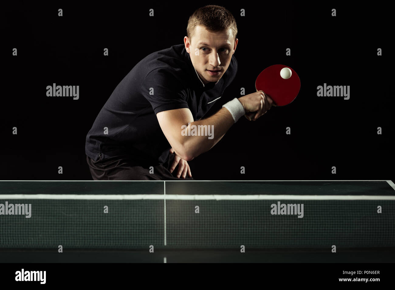 focused tennis player playing table tennis isolated on black Stock ...