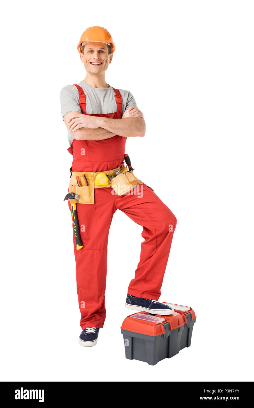 Builder with tools in belt standing with folded arms isolated on white ...