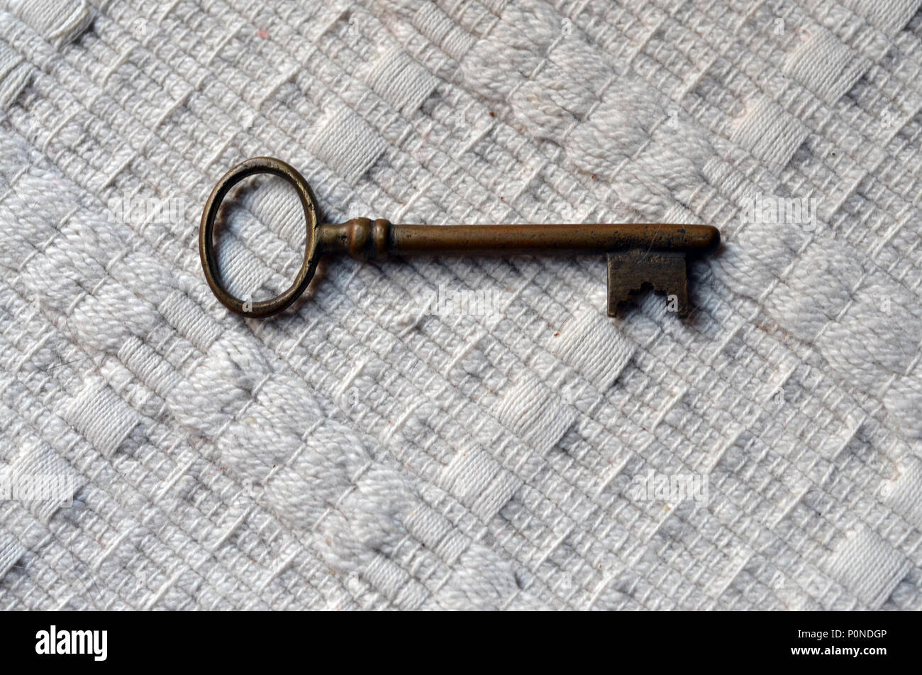An antique brass key on a white fabric background Stock Photo - Alamy