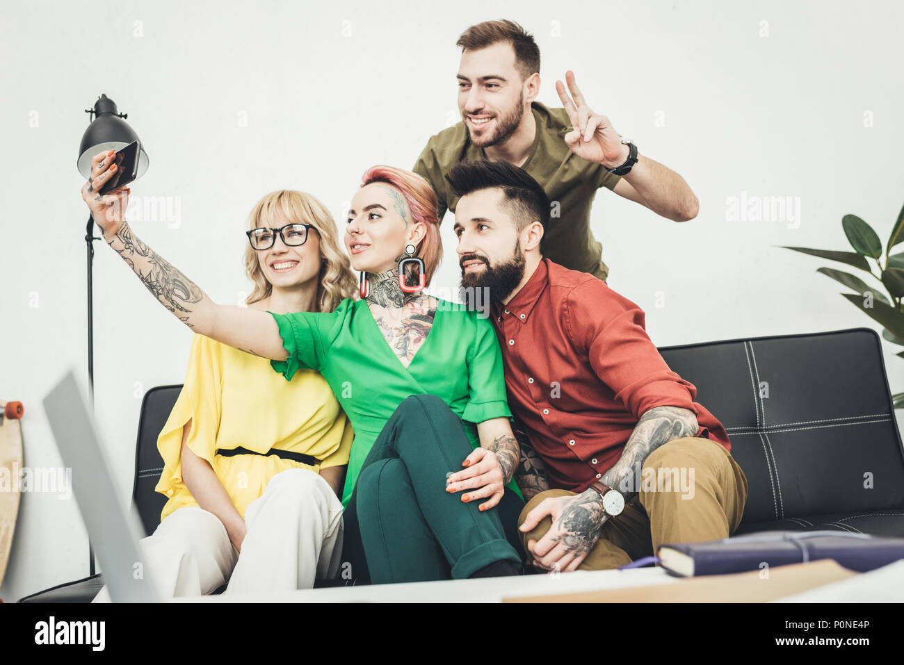 portrait of group of creative workers taking selfie on smartphone ...