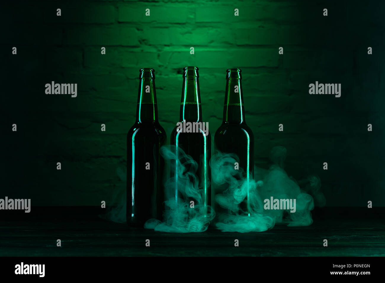 three green beer bottles and smoke in green light Stock Photo - Alamy