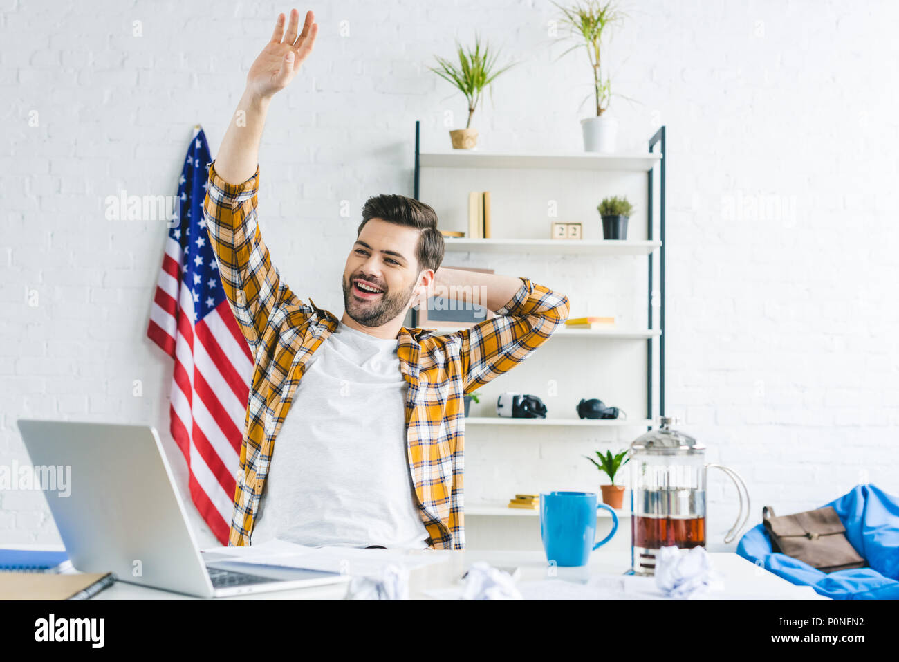 Smiling man stretching by working table at home office Stock Photo - Alamy