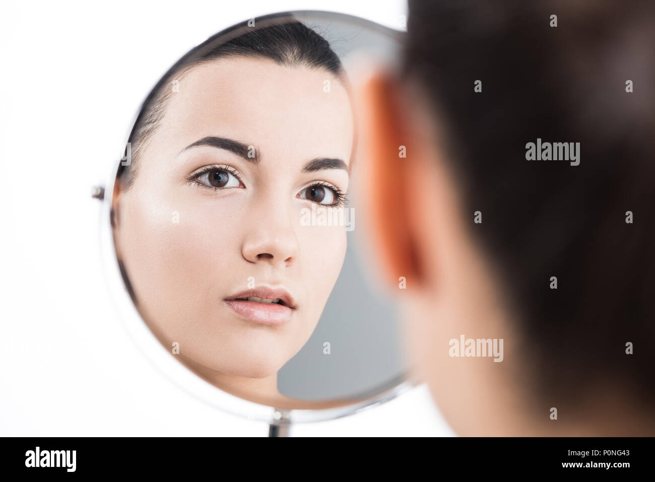 back view of beautiful girl looking at table mirror isolated on white ...