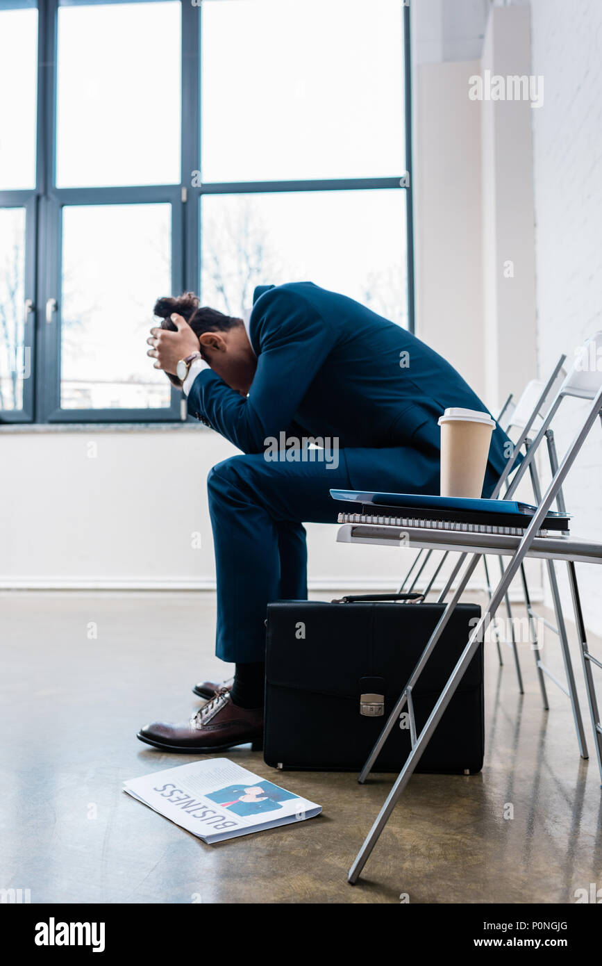 Upset man sitting on chair by stack of documents and coffee cup Stock ...