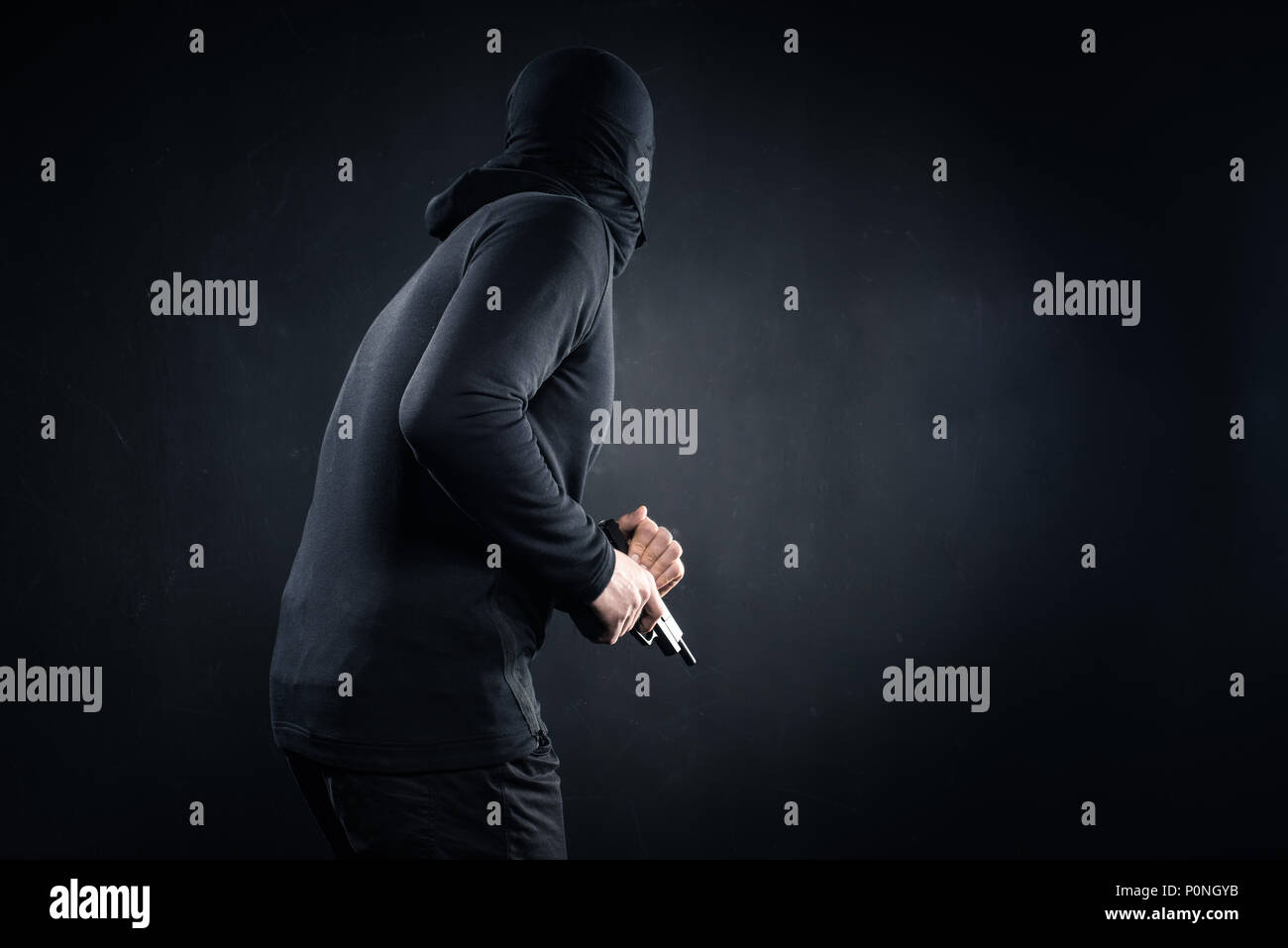 Robber with gun sneaking on black background Stock Photo - Alamy