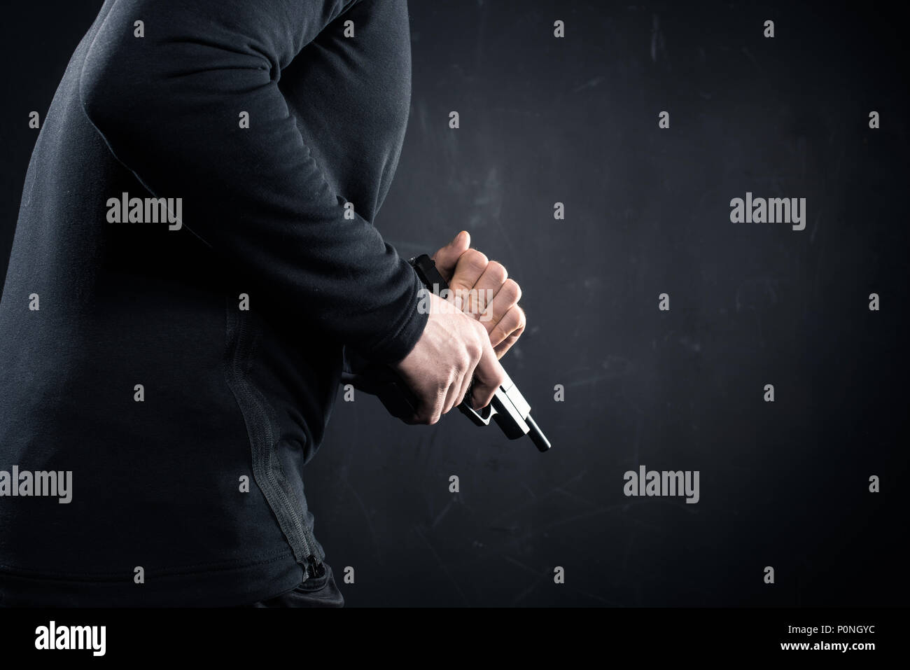 Robber in black closes holding gun in hands Stock Photo - Alamy