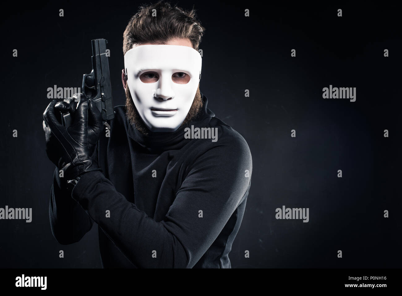 Criminal in white mask and black clothes holding gun Stock Photo - Alamy