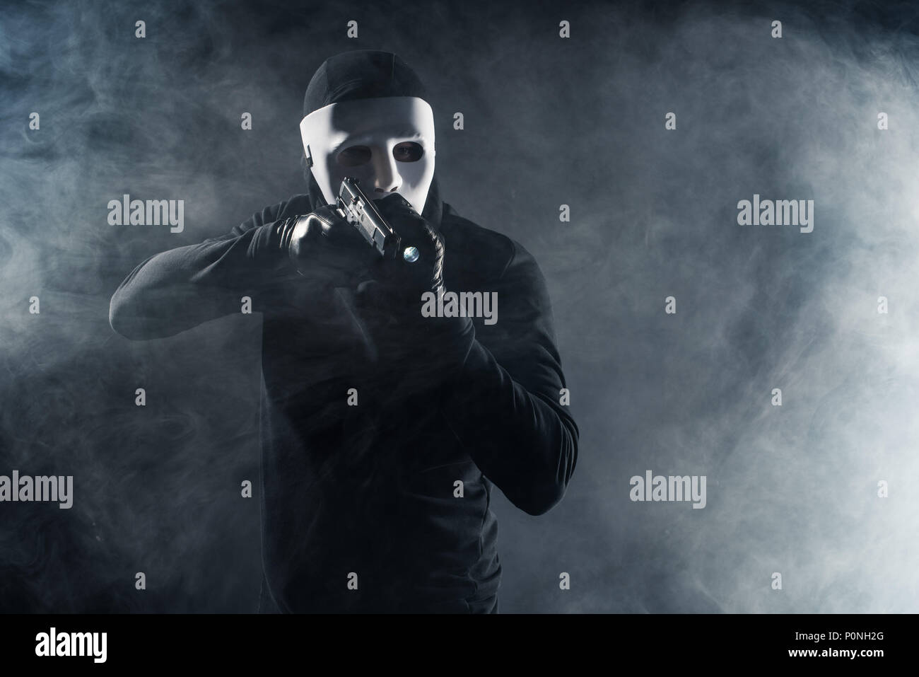 Man in mask and balaclava aiming with gun and flashlight Stock Photo ...