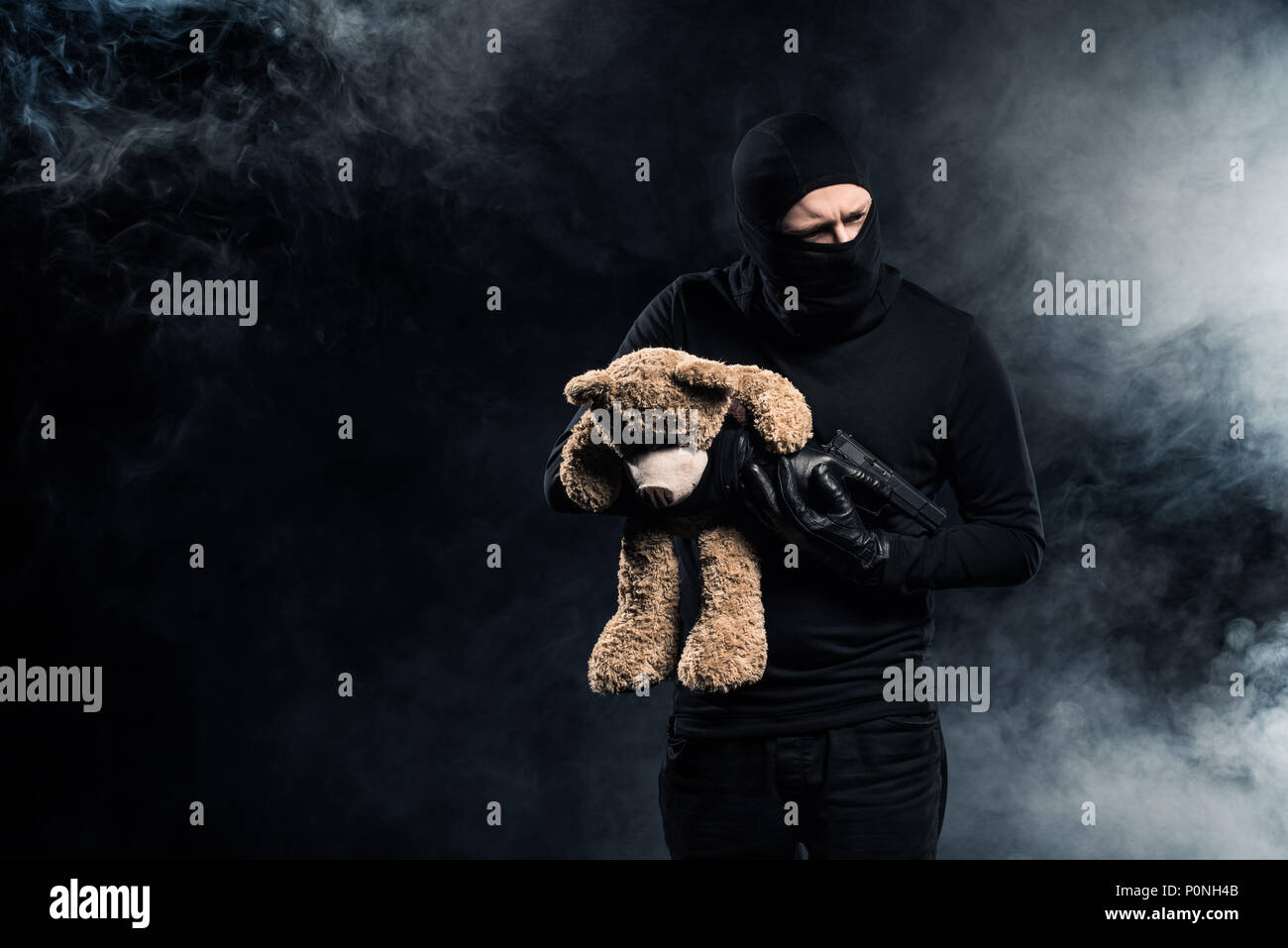 Kidnapper in balaclava holding gun and teddy bear Stock Photo - Alamy