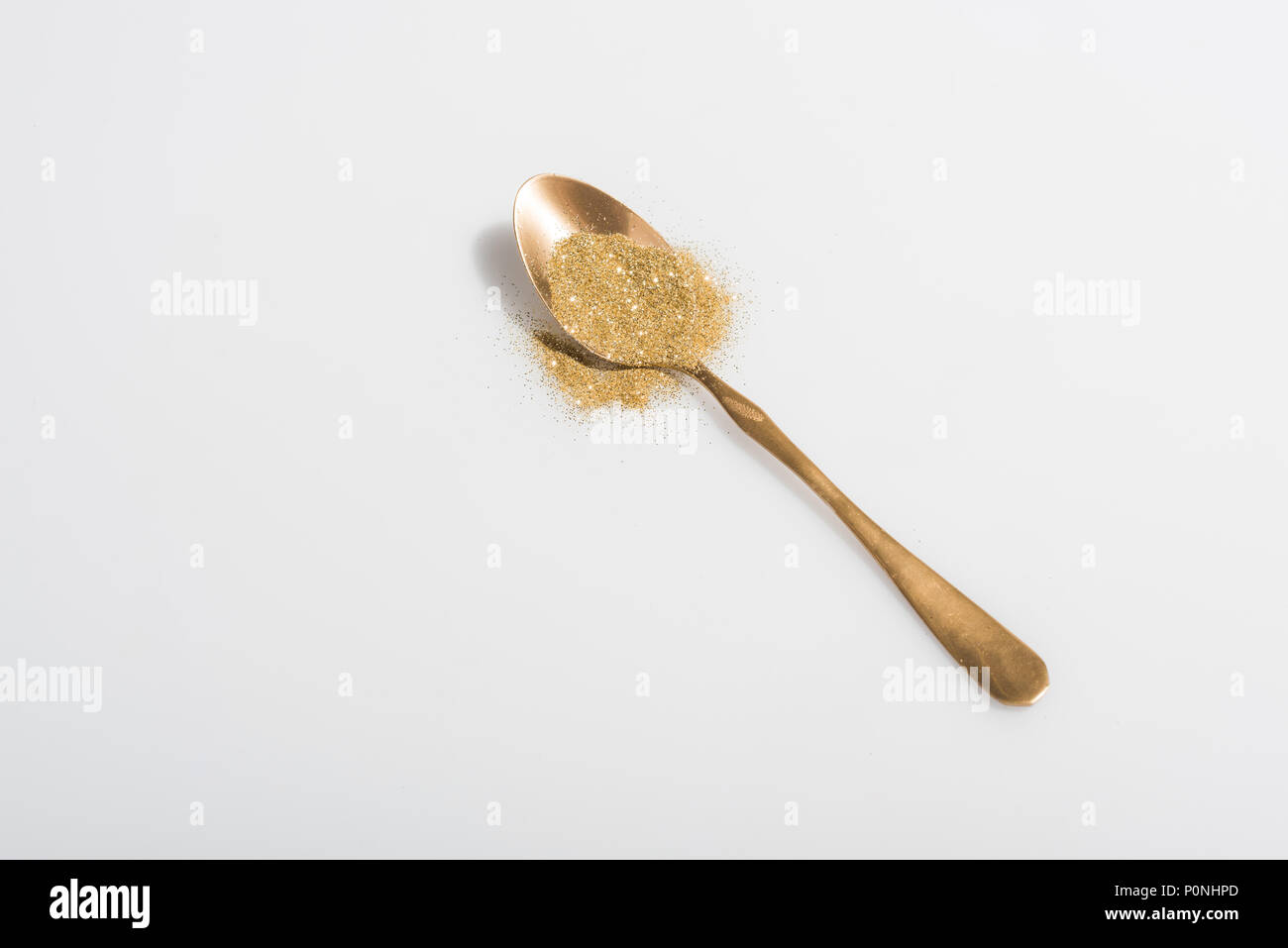 golden spoon and bright sand on white Stock Photo - Alamy