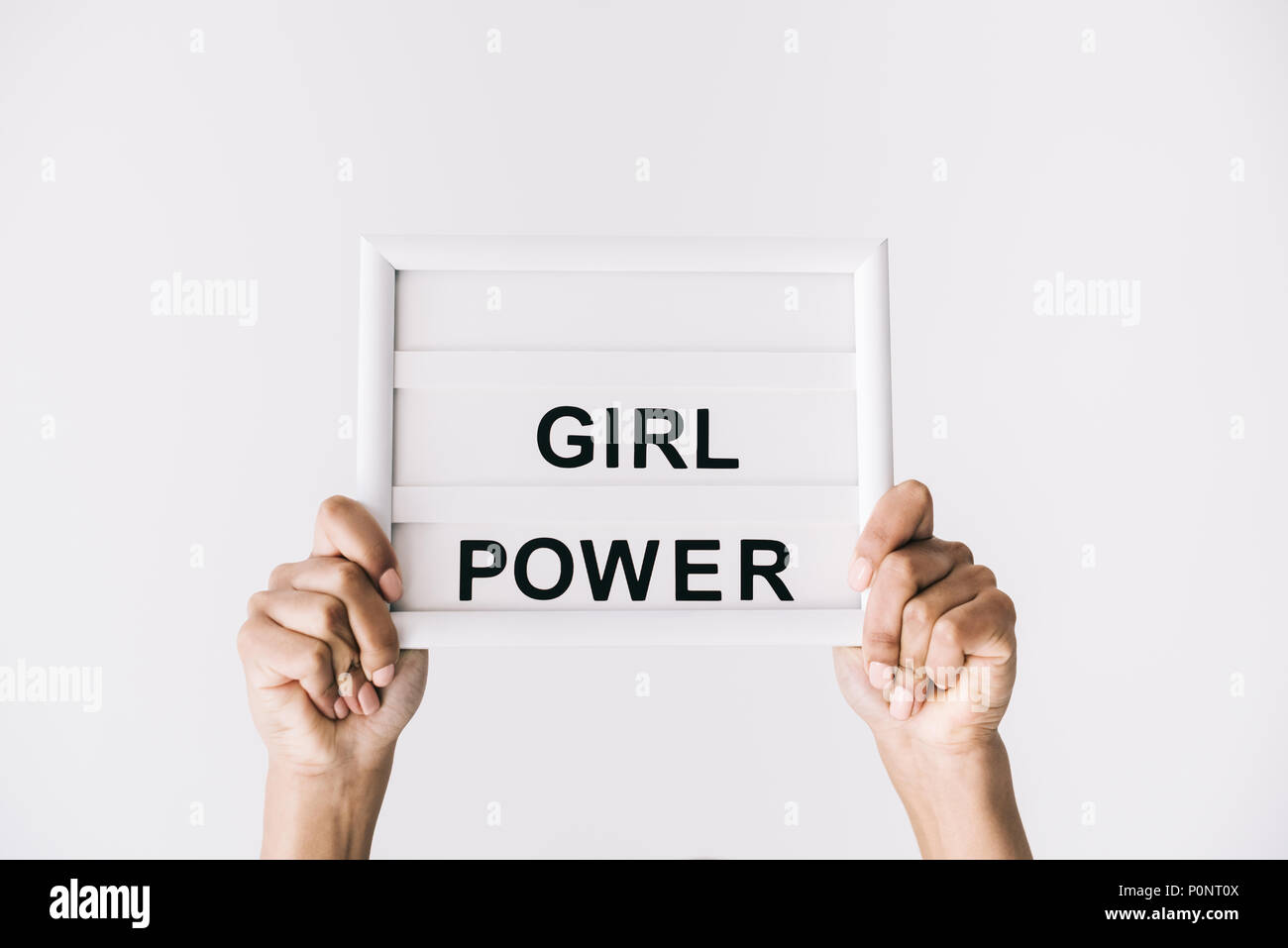 partial view of female hands holding board with girl power lettering ...