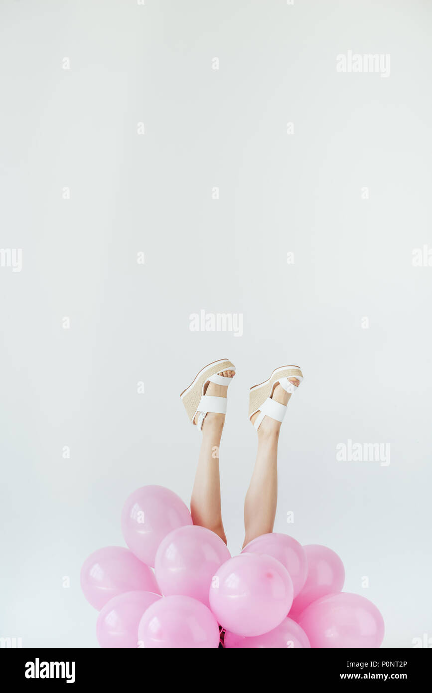 partial view of female legs and bunch of balloons isolated on grey ...