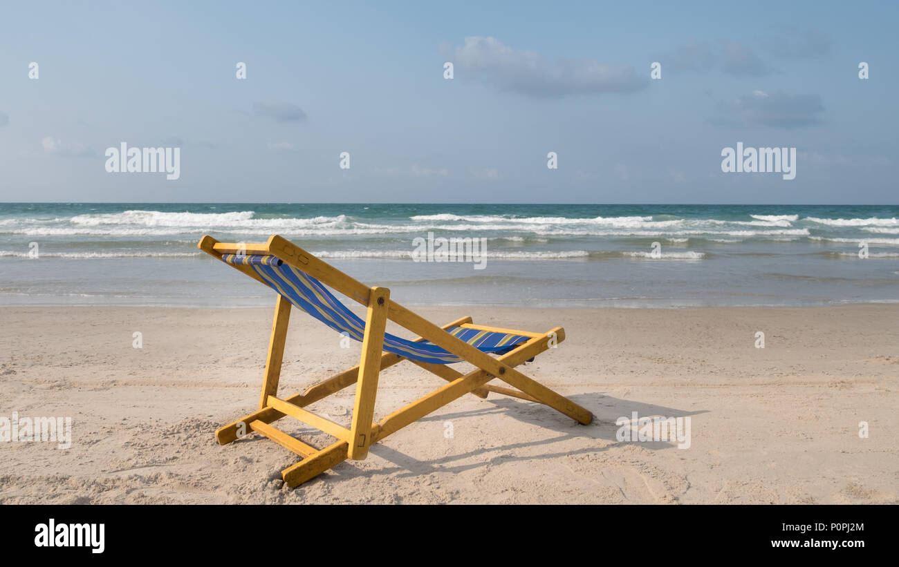 An yellow beach chair rests on the white sand of the beach and Bright ...