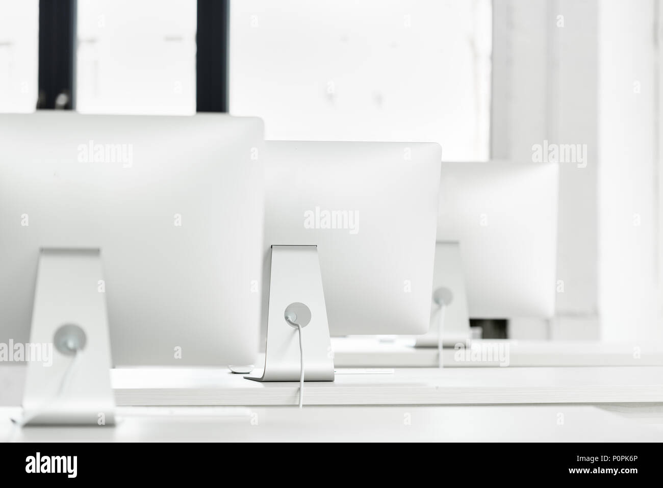 close up view of white computer monitors standing on tables in computer ...