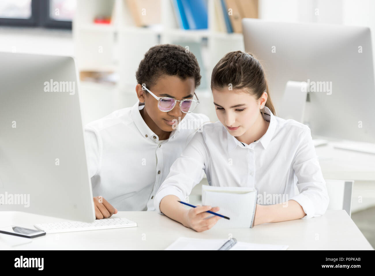 portrait of multicultural students doing task together while sitting at ...