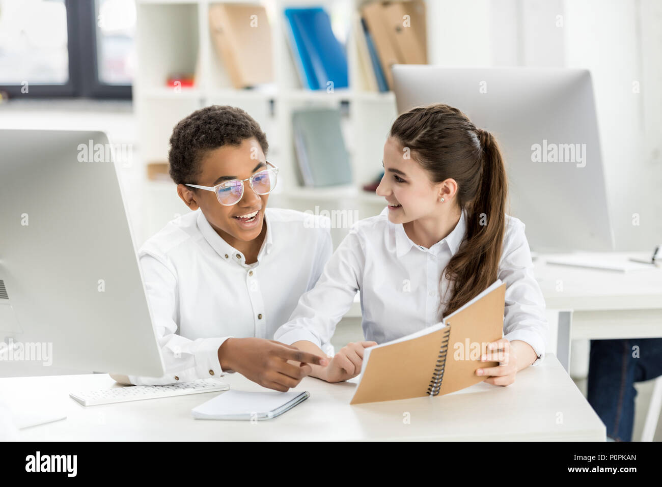 portrait of multicultural students doing task together while sitting at ...