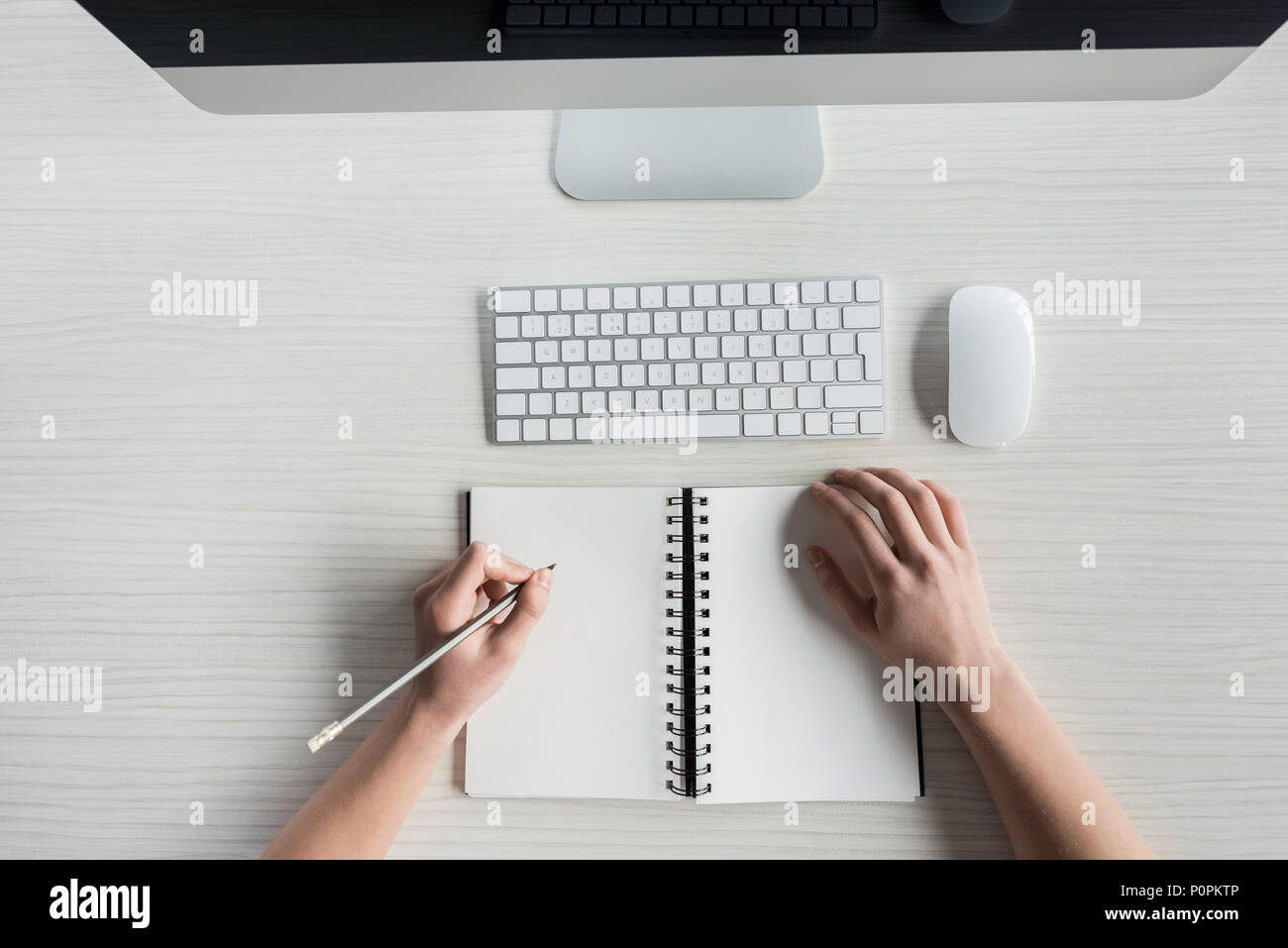 partial view of student writing in notebook and using digital devices ...