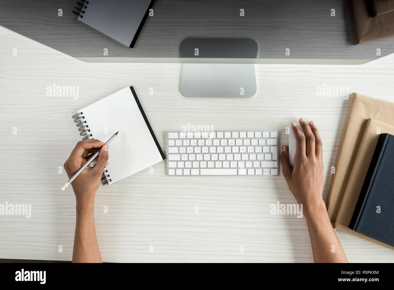 partial view of student writing in notebook and using digital devices ...