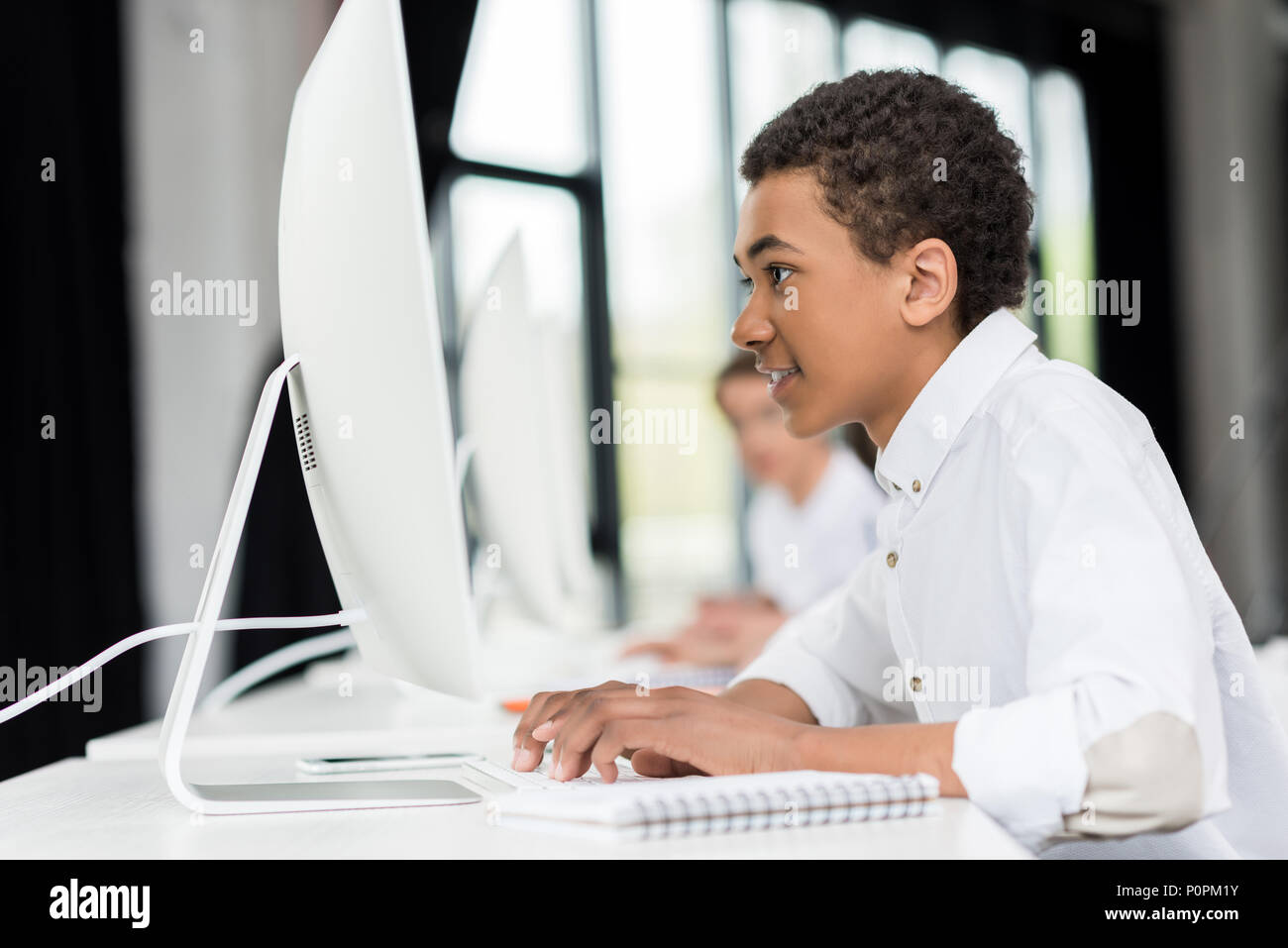 side view of african american teen boy typing on keyboard in front of ...