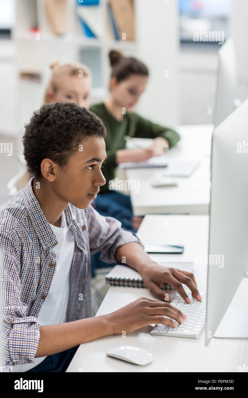 side view of african american teen boy typing on keyboard in front of ...