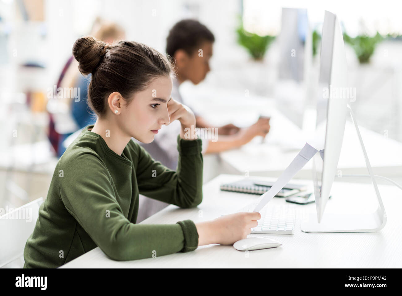side view of focused teenage student looking at test paper in class ...