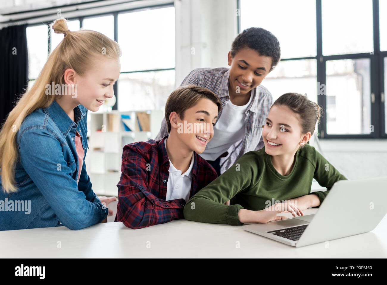 multiethnic group of teenagers using laptop together in class Stock ...