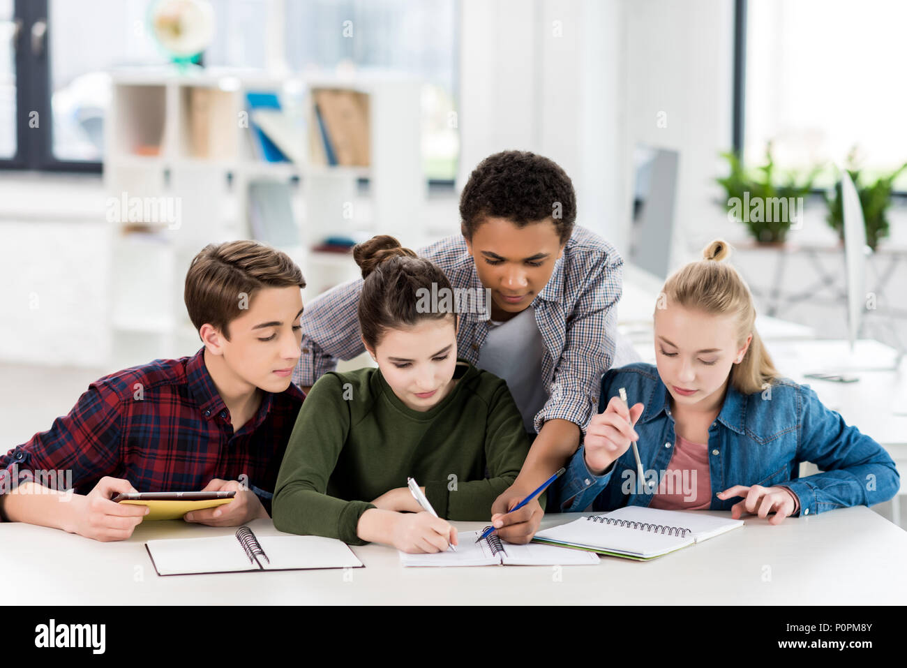 multiethnic group of teenagers doing homework together in class Stock ...